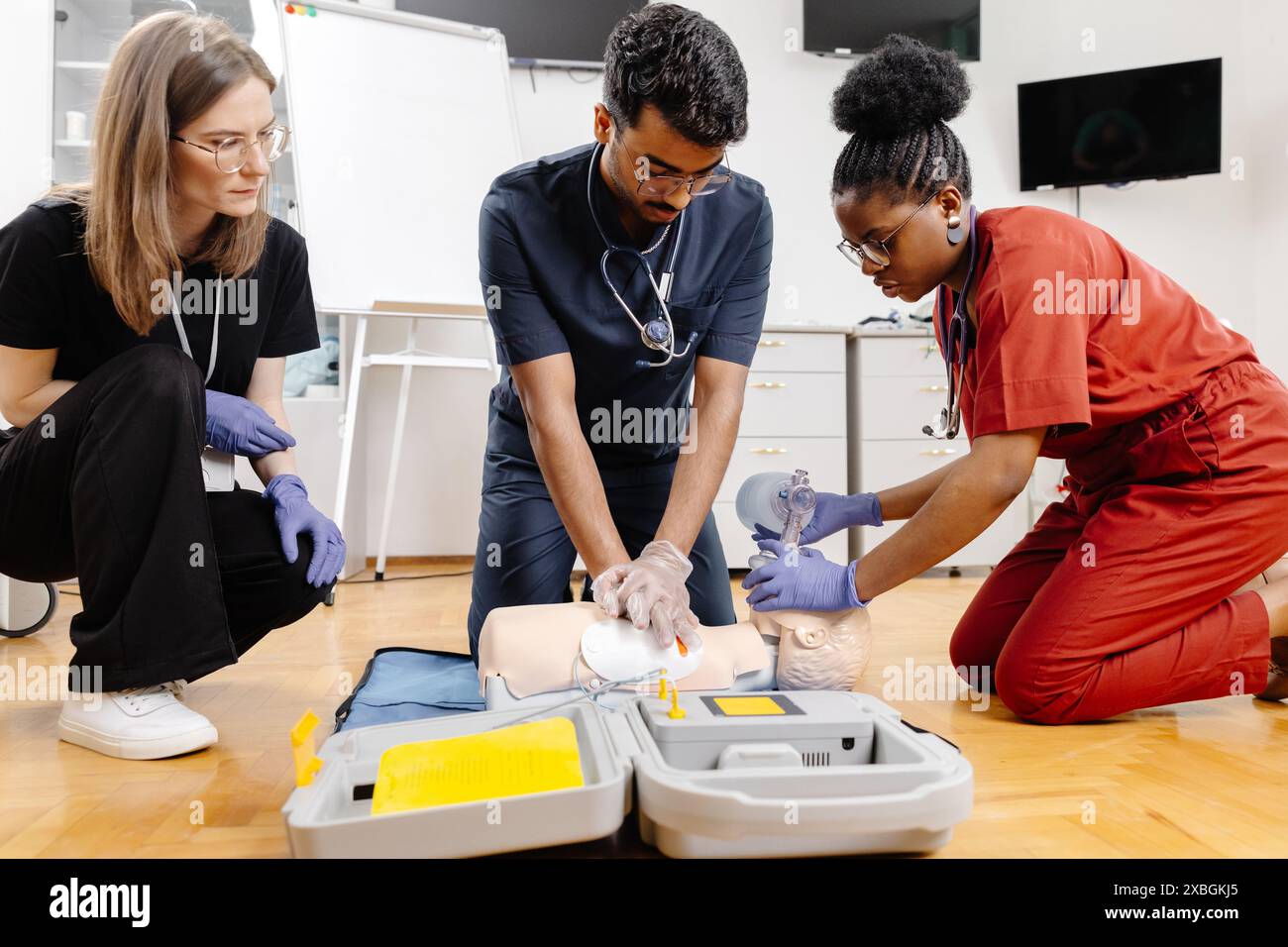 Three individuals practice CPR techniques on a training dummy in a ...