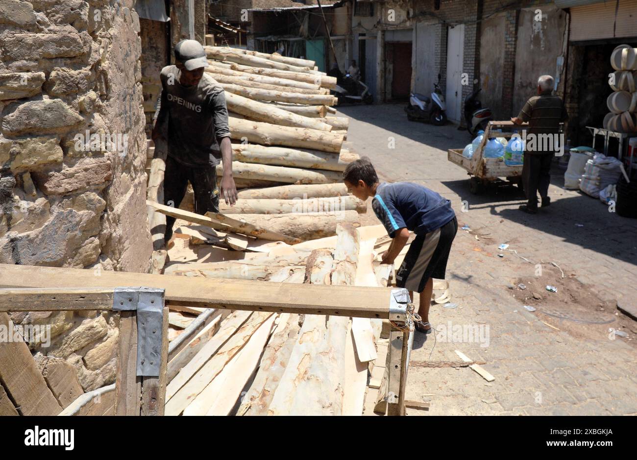 Baghdad, Iraq. 8th June, 2024. Salih, 12, loads wood onto his cart in a ...