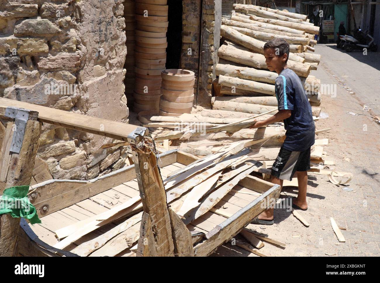 Baghdad, Iraq. 8th June, 2024. Salih, 12, loads wood onto his cart in a ...