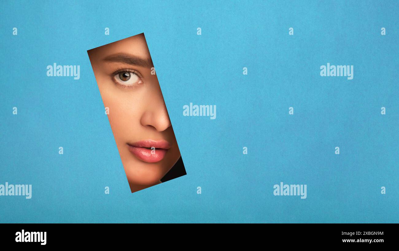 Beautiful Woman Face Peeking Through Hole in Blue Wall Stock Photo - Alamy
