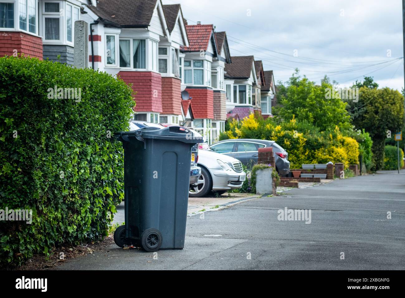 LONDON- JUNE 10, 2024: Black wheeler bin refuse rubbish bin in ...