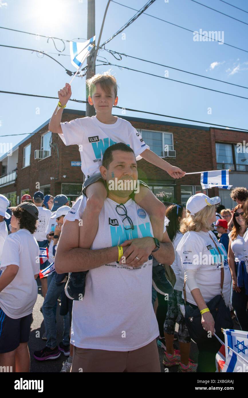 A boy holding Israel flag sits on his father’s shoulders during UJA ...