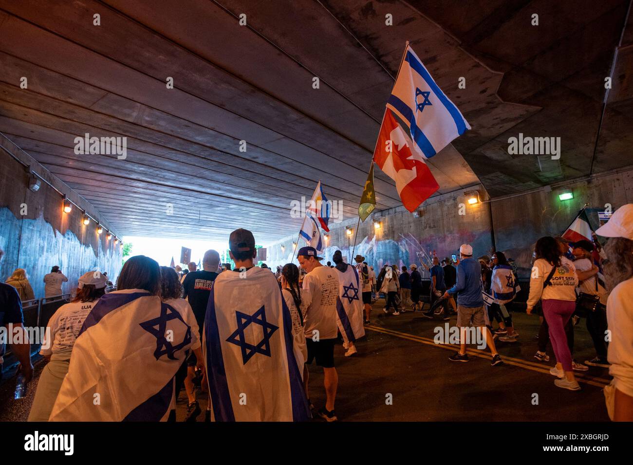 People draped in Israel flags walk under bridge during UJA (United ...