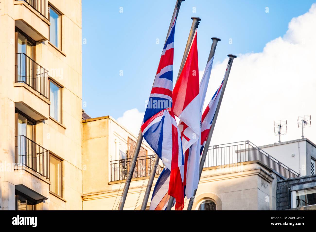 Flags United Kingdom and Canada flutter against backdrop building facades, international ...