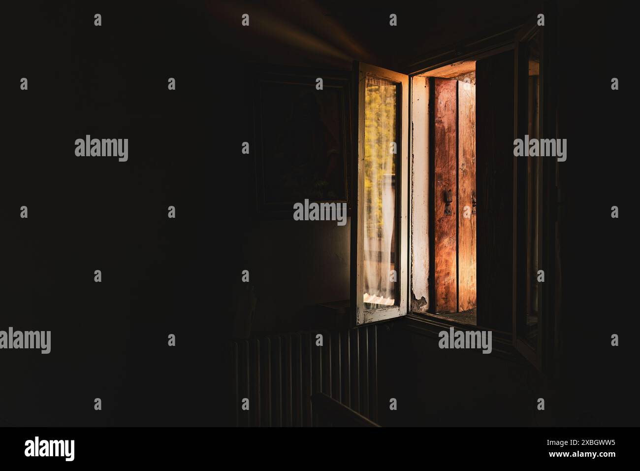 Sunlight streaming through an open window in a dark, old room, creating ...