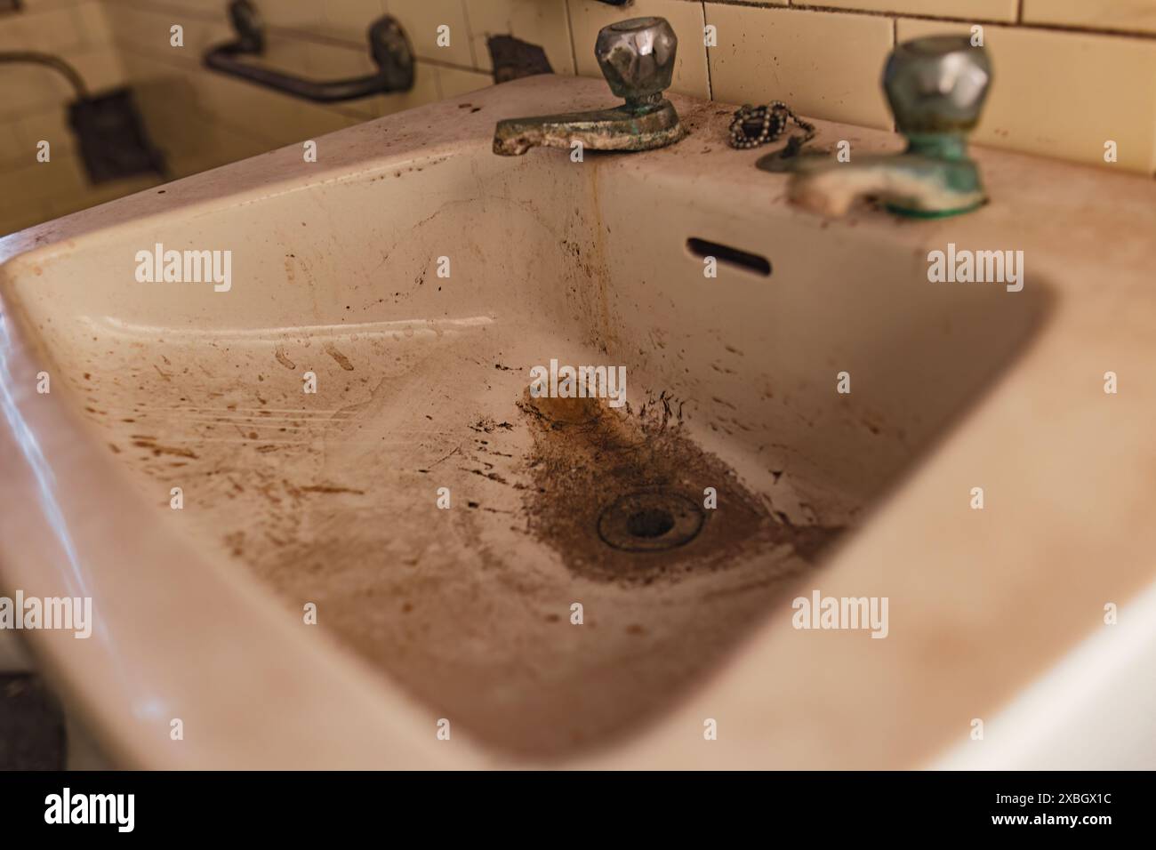 Close-up of a dirty, stained sink in an abandoned bathroom with yellow ...