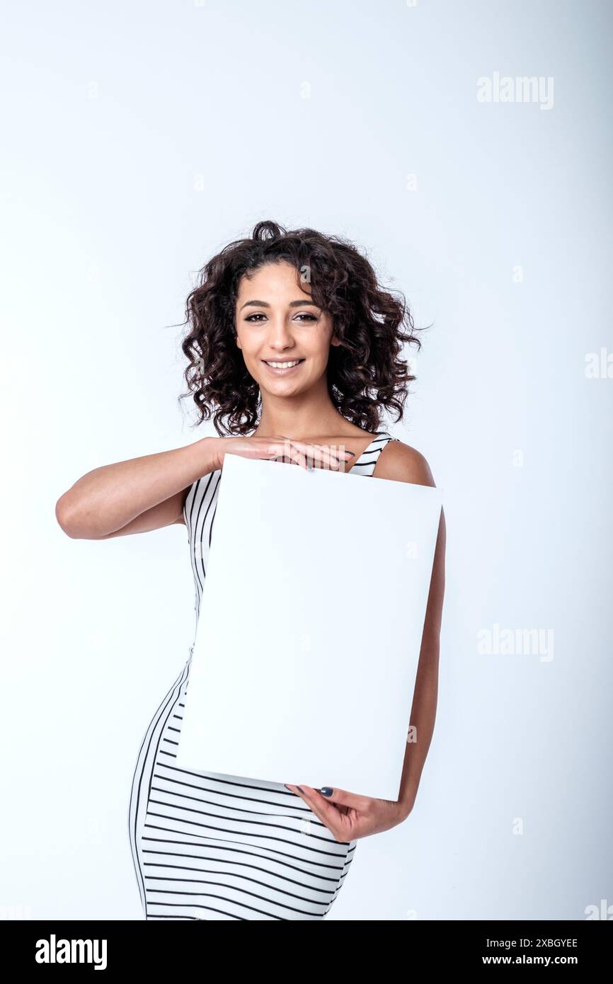 Portrait oriented studio image of a curly haired brunette woman holding ...