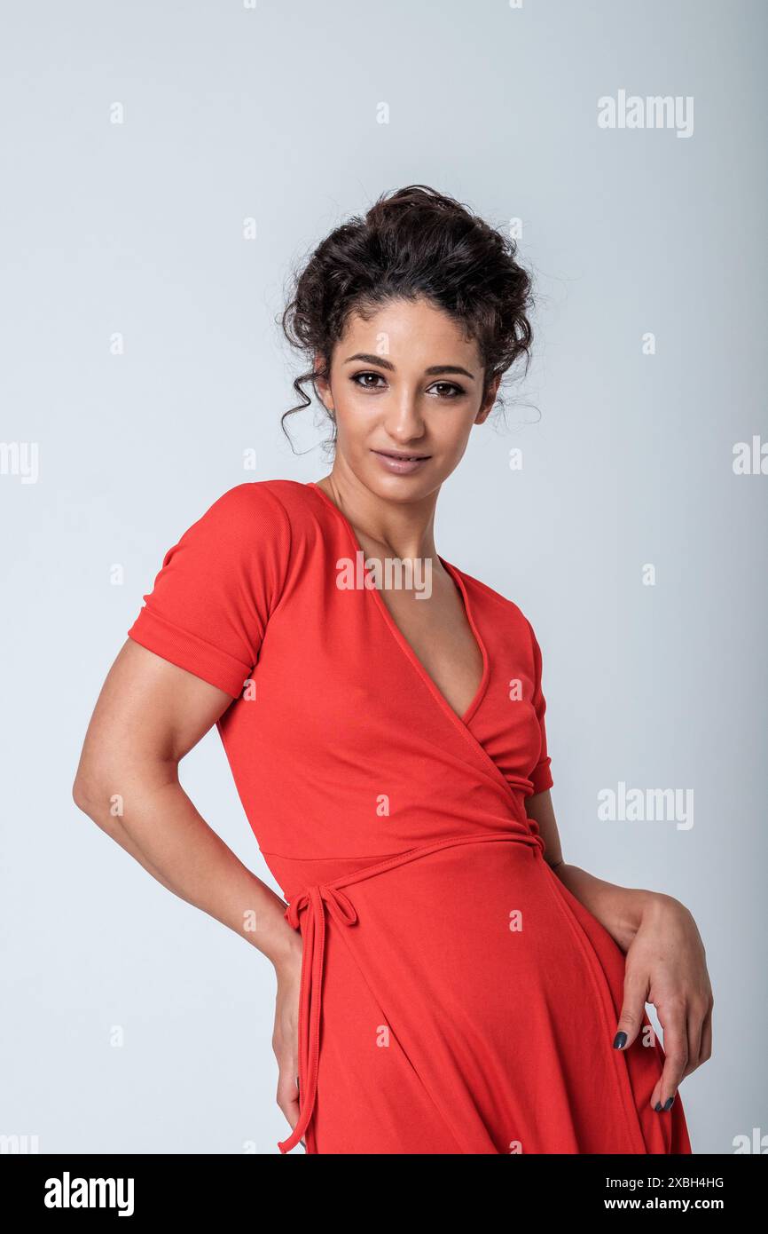 A ravishingly beautiful woman in her mid 20s wears a simple red dress ...