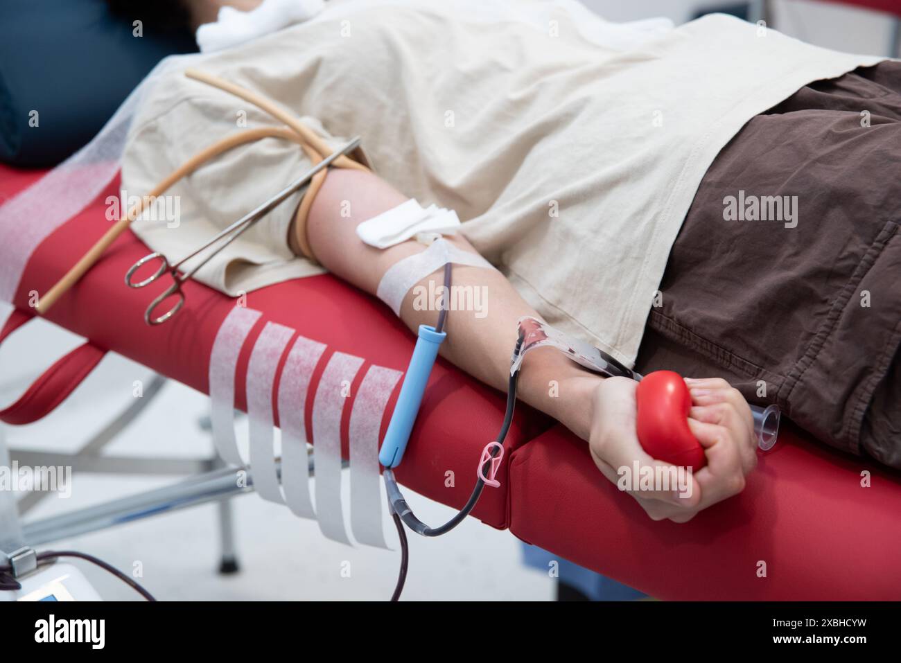 Hand of unrecognizable blood donor squeezing red heart-shaped rubber ...