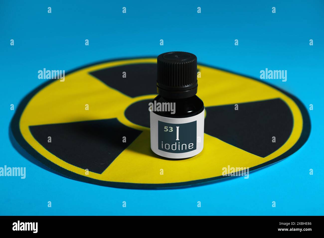 Bottle of medical iodine and radiation sign on light blue background ...