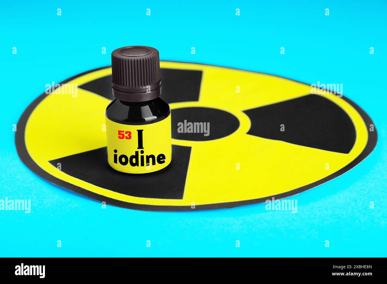 Bottle of medical iodine and radiation sign on light blue background ...
