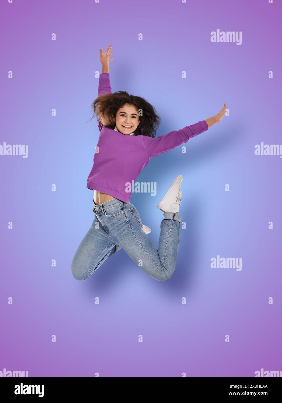 Positive young woman jumping on blue purple gradient background Stock ...