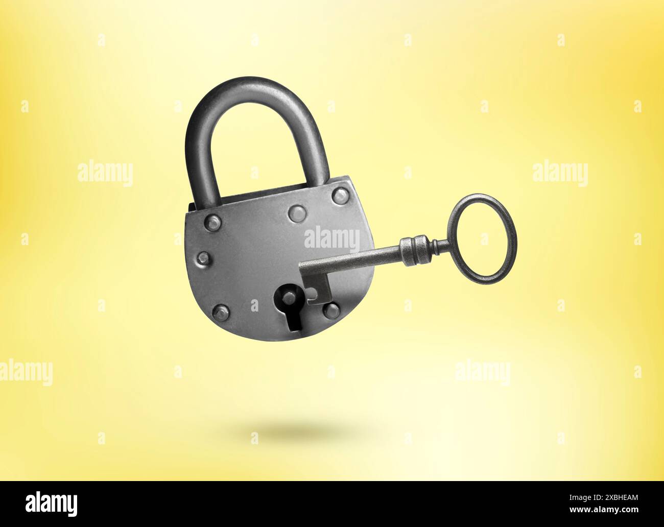 Padlock and key in air on yellow background Stock Photo - Alamy