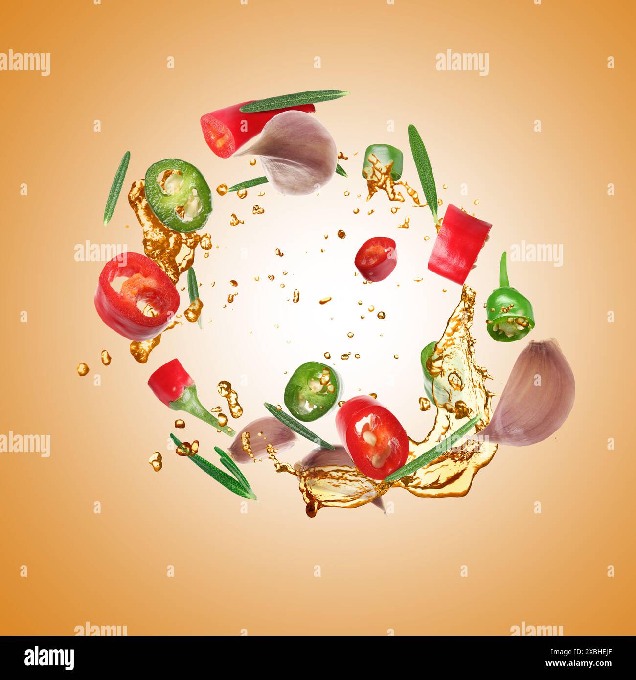 Cooking oil splash with chili peppers, garlic and rosemary in air on ...