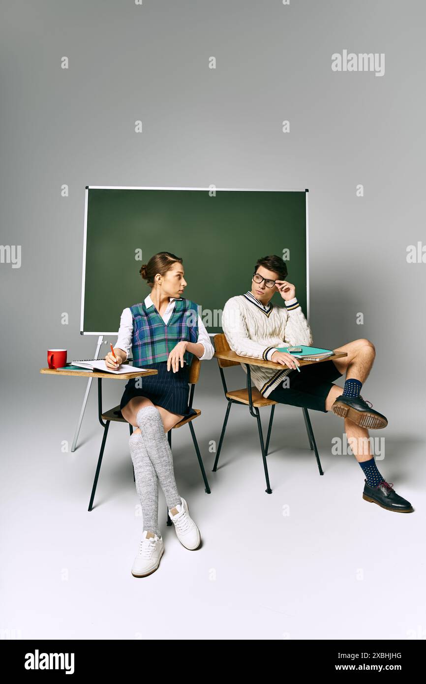 Elegant man and woman seated by a green board in a college setting ...