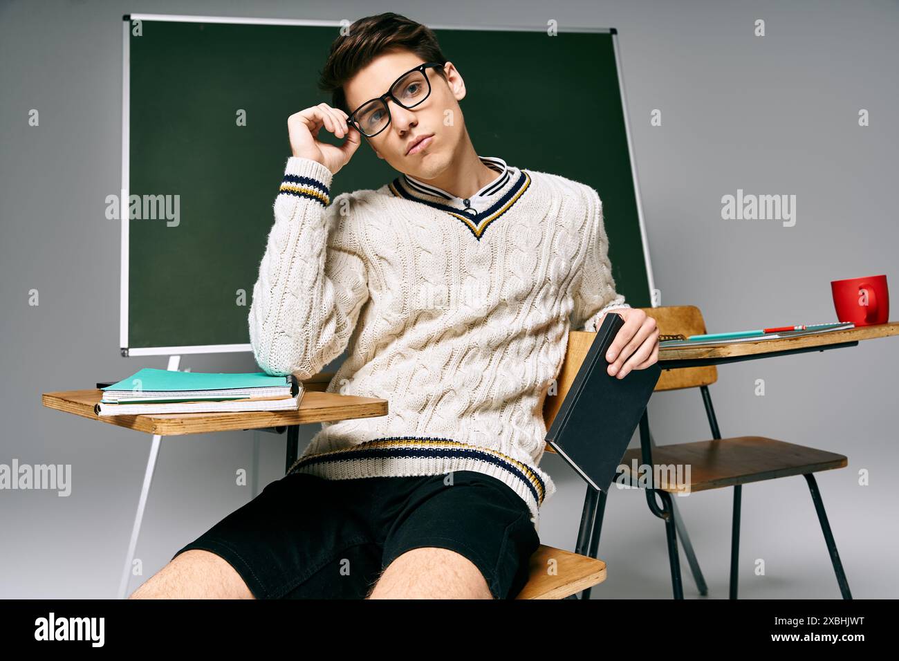 Young man in deep thought sitting by a green board Stock Photo - Alamy