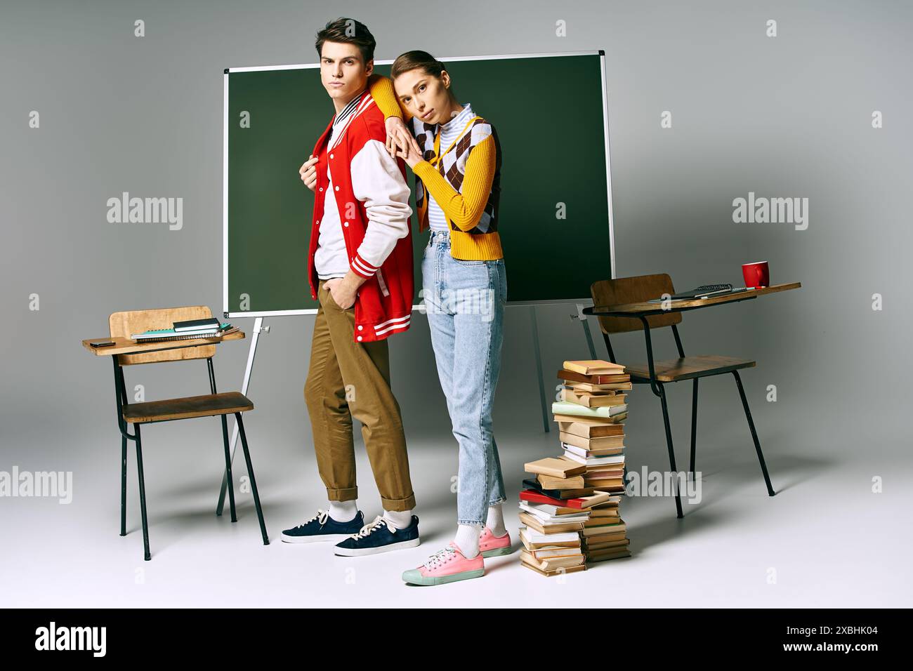 A man and a woman in stylish attire posing confidently in a classroom ...