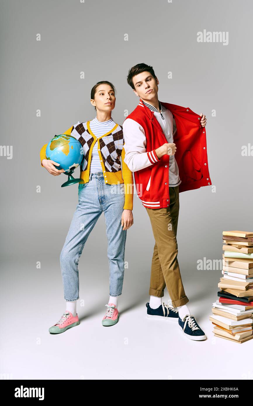 Two students, male and female students, stand next to a stack of books ...