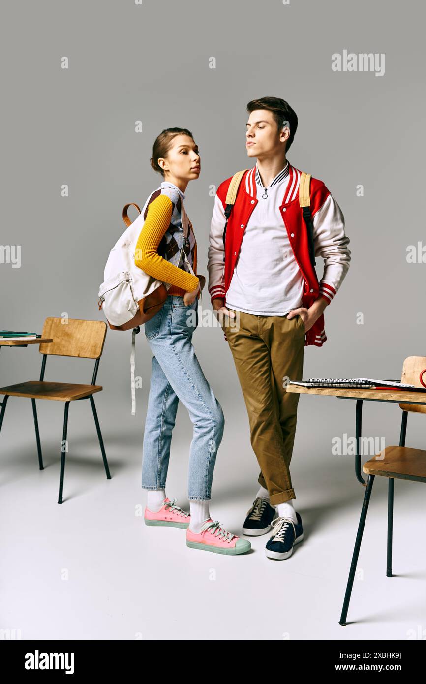 A male and female students in casual attire pose in a classroom setting ...