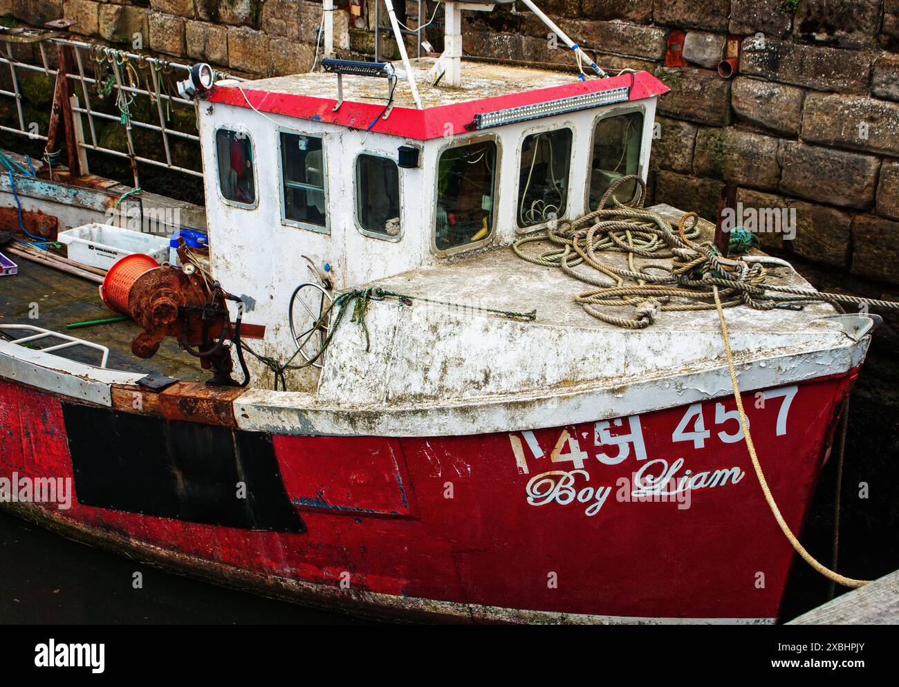 An old patched fishing boat in the harbour at Amble, Northumberland, UK ...