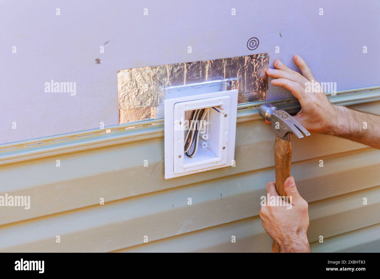 Installing vinyl plastic siding panels on facade of new house by an ...