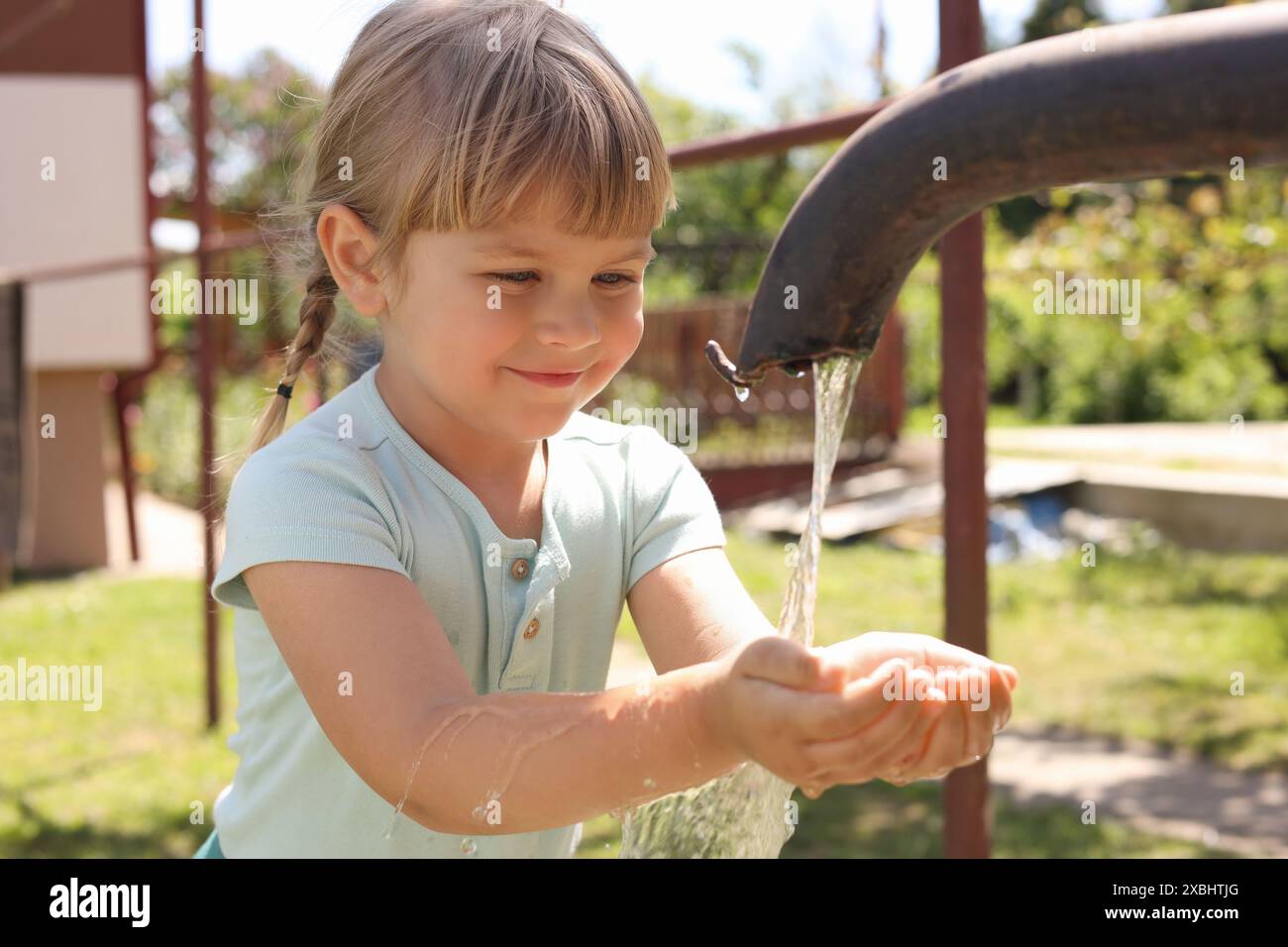 Water scarcity. Cute little girl drawing water with hands from tap ...