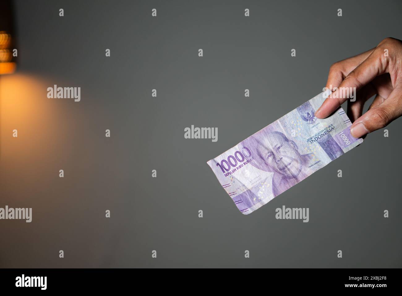 A hand holding a 1000 South African Rand banknote against a plain ...