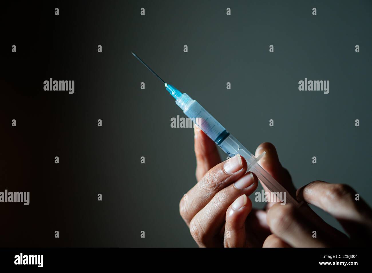 Close-up of hands holding a syringe with a needle, preparing for ...