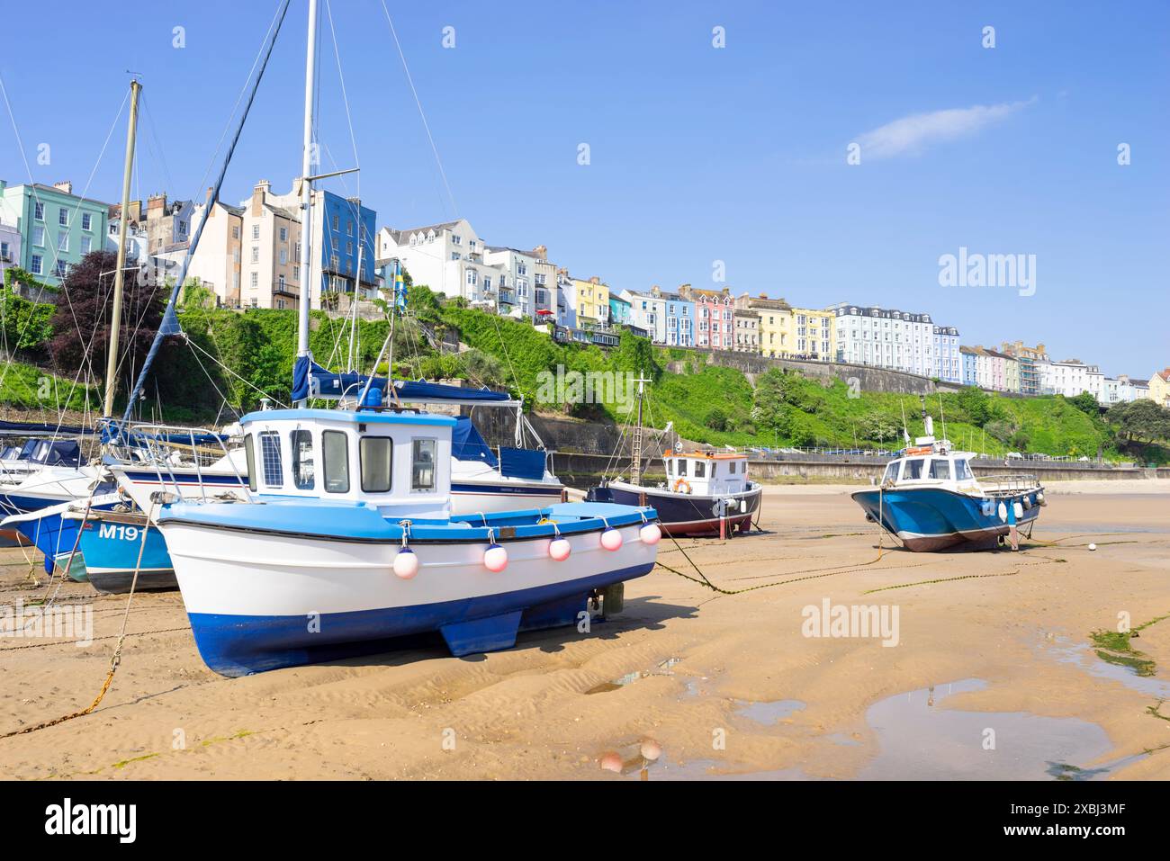Tenby Harbour small boats moored at low tide and Tenby colourful houses ...