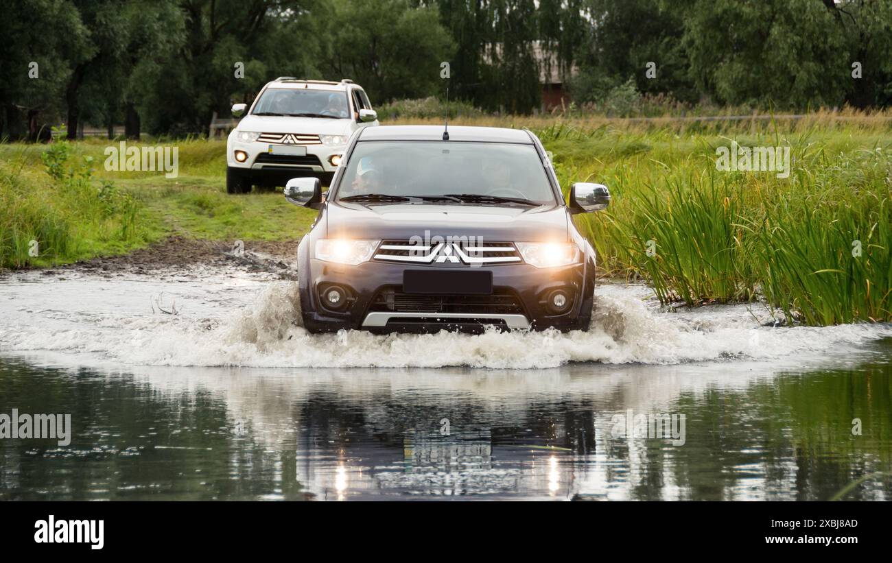 Black truck fording a river, plashes scatter in all directions ...