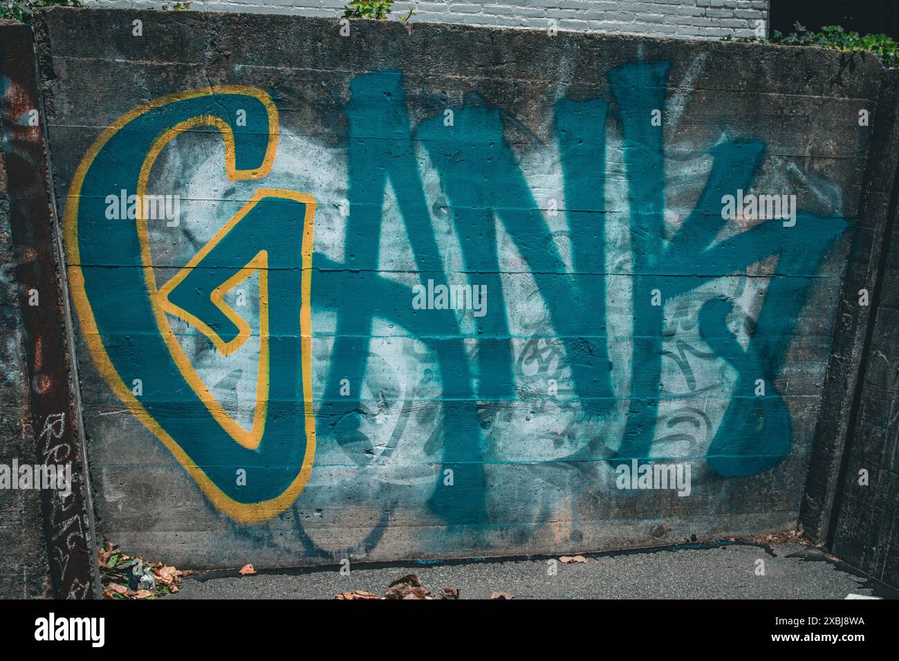 A concrete block wall with aged blue and yellow graffiti spray paint ...