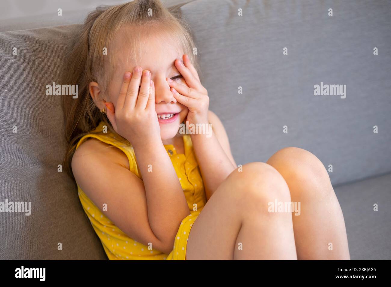 sweet child, shy blonde girl playful covers eyes with hands, capturing Playful innocence ...