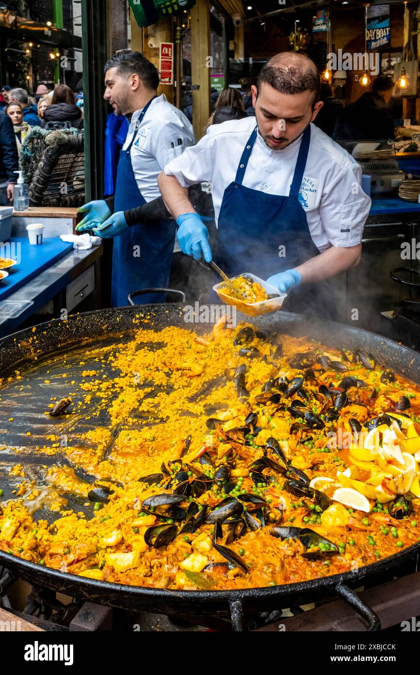 A Young Man Serving Paella From A Large Dish At Borough Market, London ...
