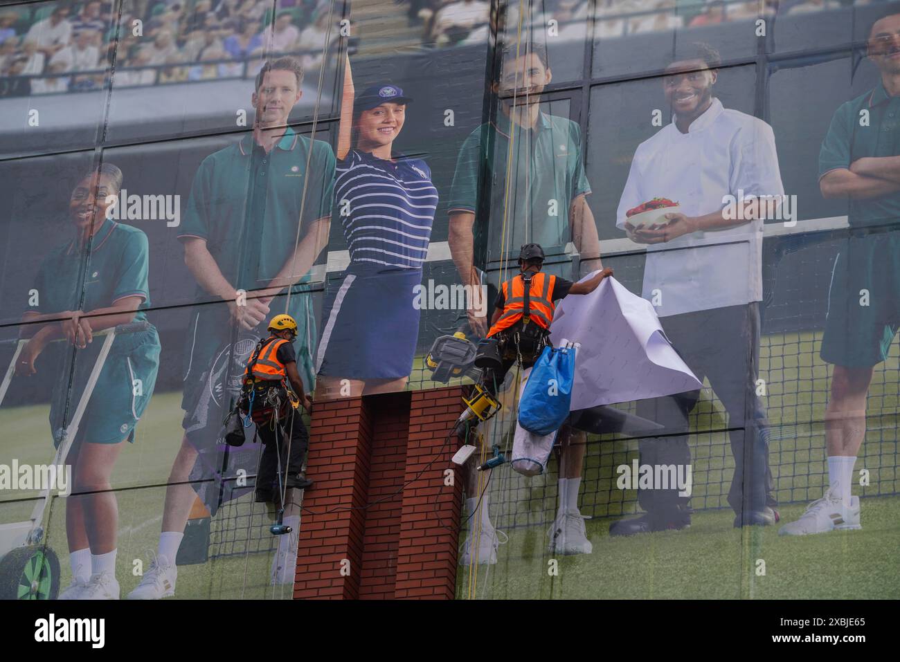 London, UK. 12 June 2024. Workers suspended on ropes cover the facade ...