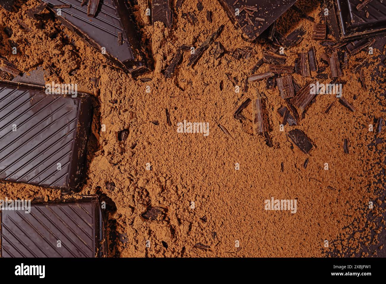 Pieces and shaves of dark bitter chocolate scattered on cocoa powder ...