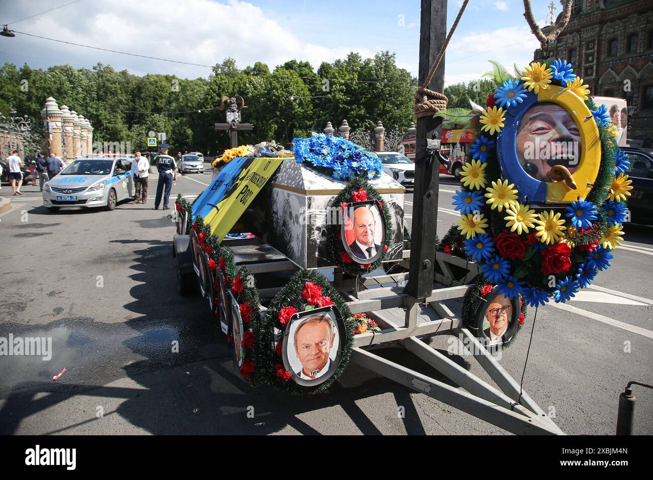 A car with a trailer in the shape of a coffin with photographs of ...