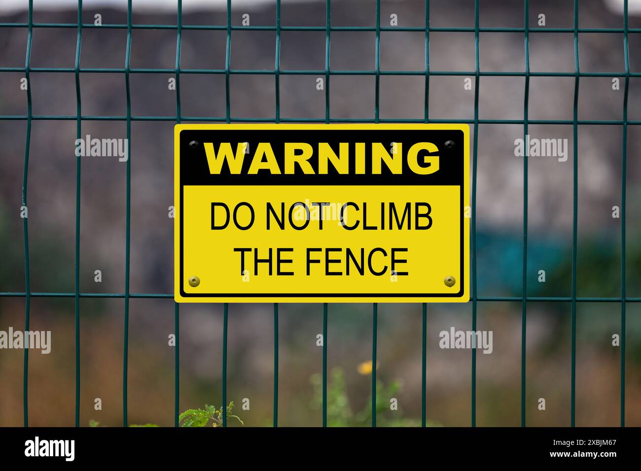 Black and Yellow warning sign attached on a fence. The sign stating ...