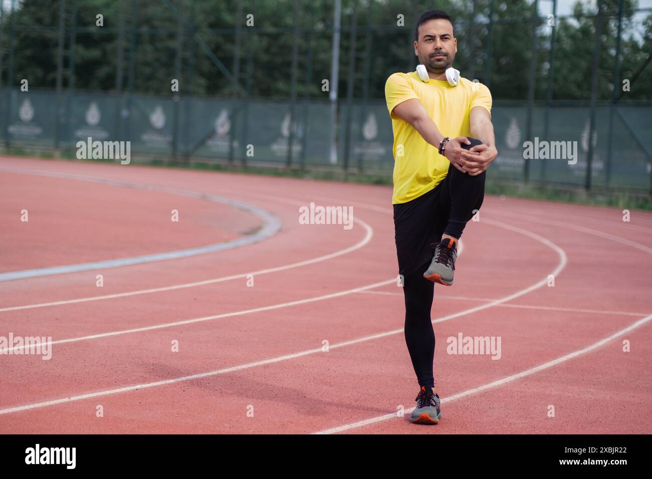Dynamic runner with wireless headphones limbers up leg muscles on ...