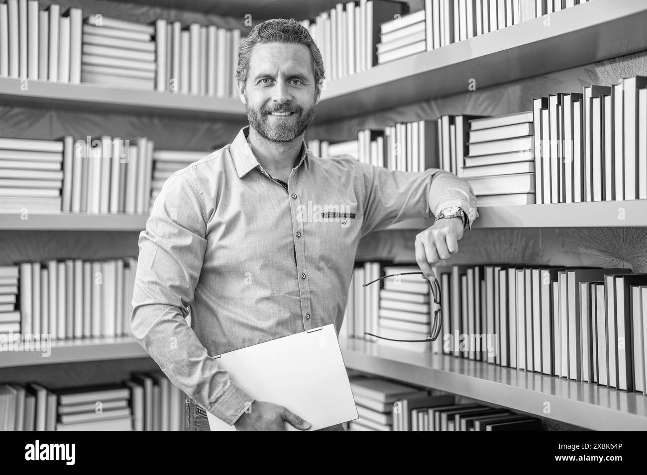 school teacher in classroom. school library full of books. man tutor at ...