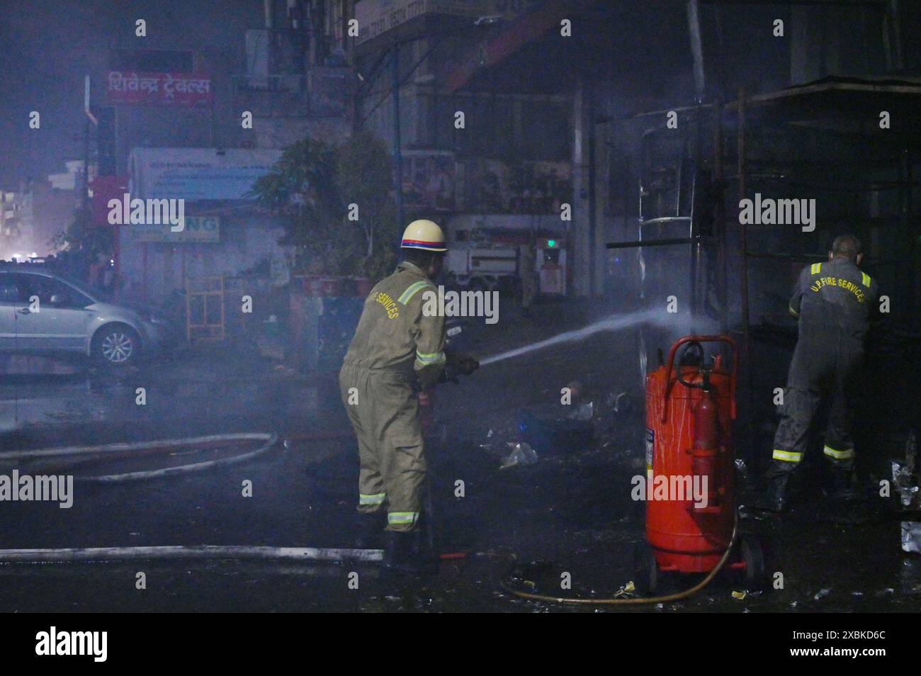 NOIDA, INDIA - JUNE 12: Fire brigade personnel extinguish the fire at shop adjacent to the ...