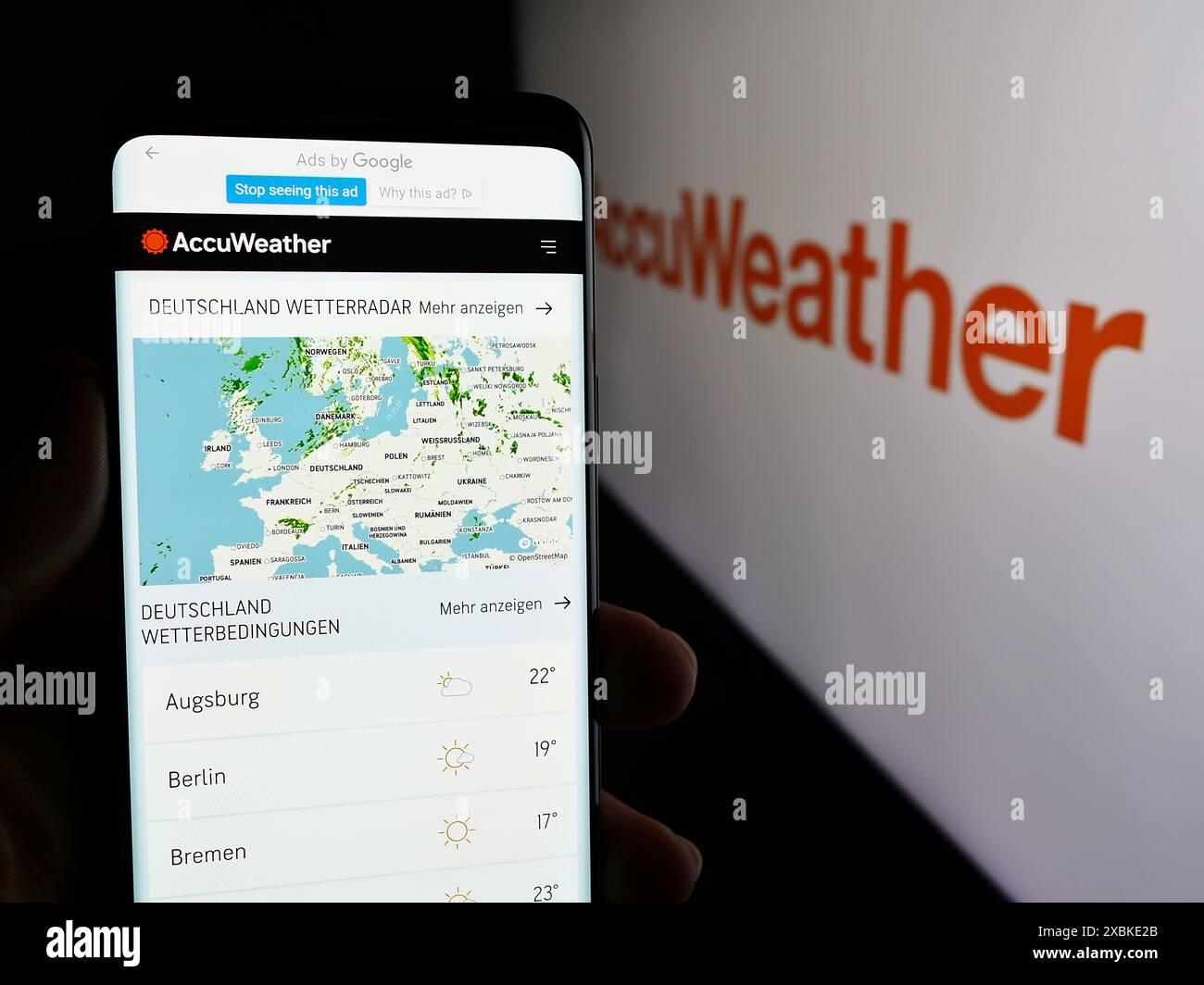 Person holding cellphone with webpage of US weather forecasting company AccuWeather Inc. in ...