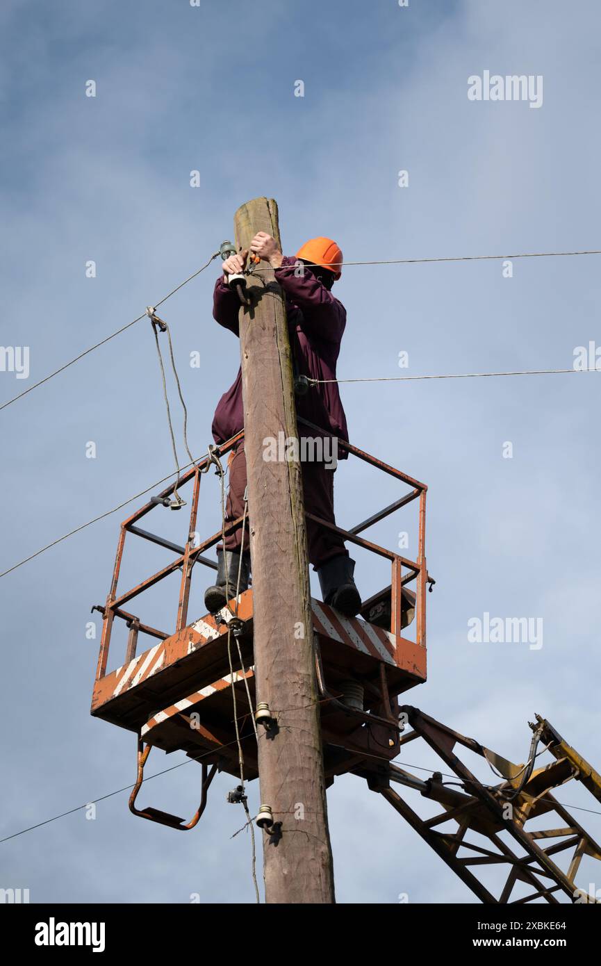 A male electrical worker repairs an electrical transmission line Stock ...