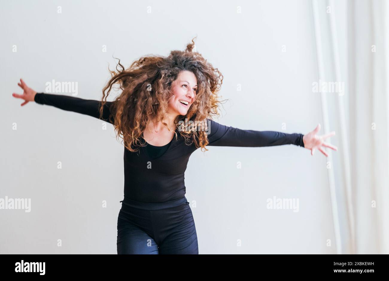woman in black outfit laughs joyfully while dancing curly hair ...