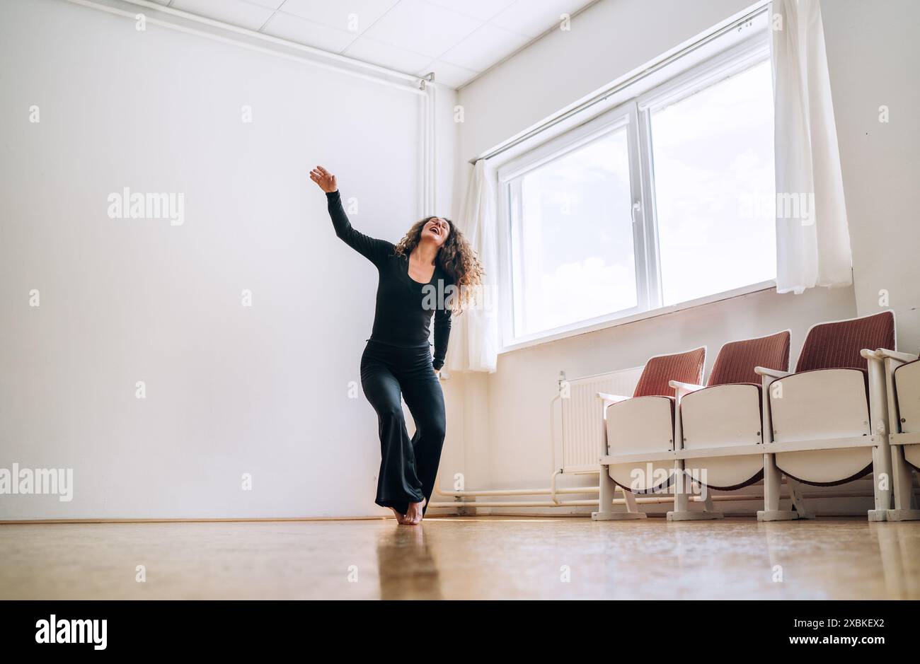 Woman in a black outfit gracefully dances in a well-lit room, her ...