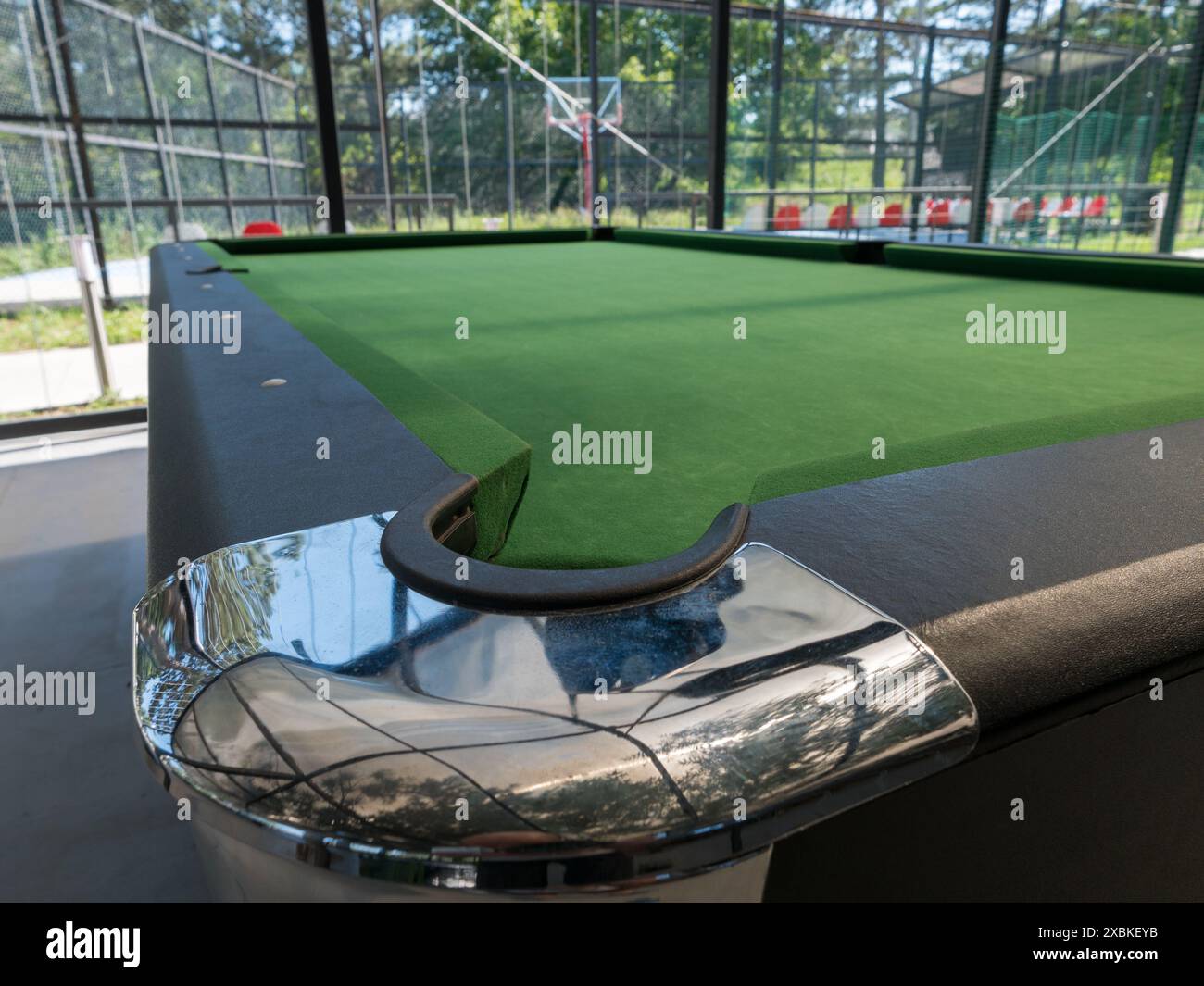 Close-up shot of a pool table corner with a chrome bumper, green felt ...