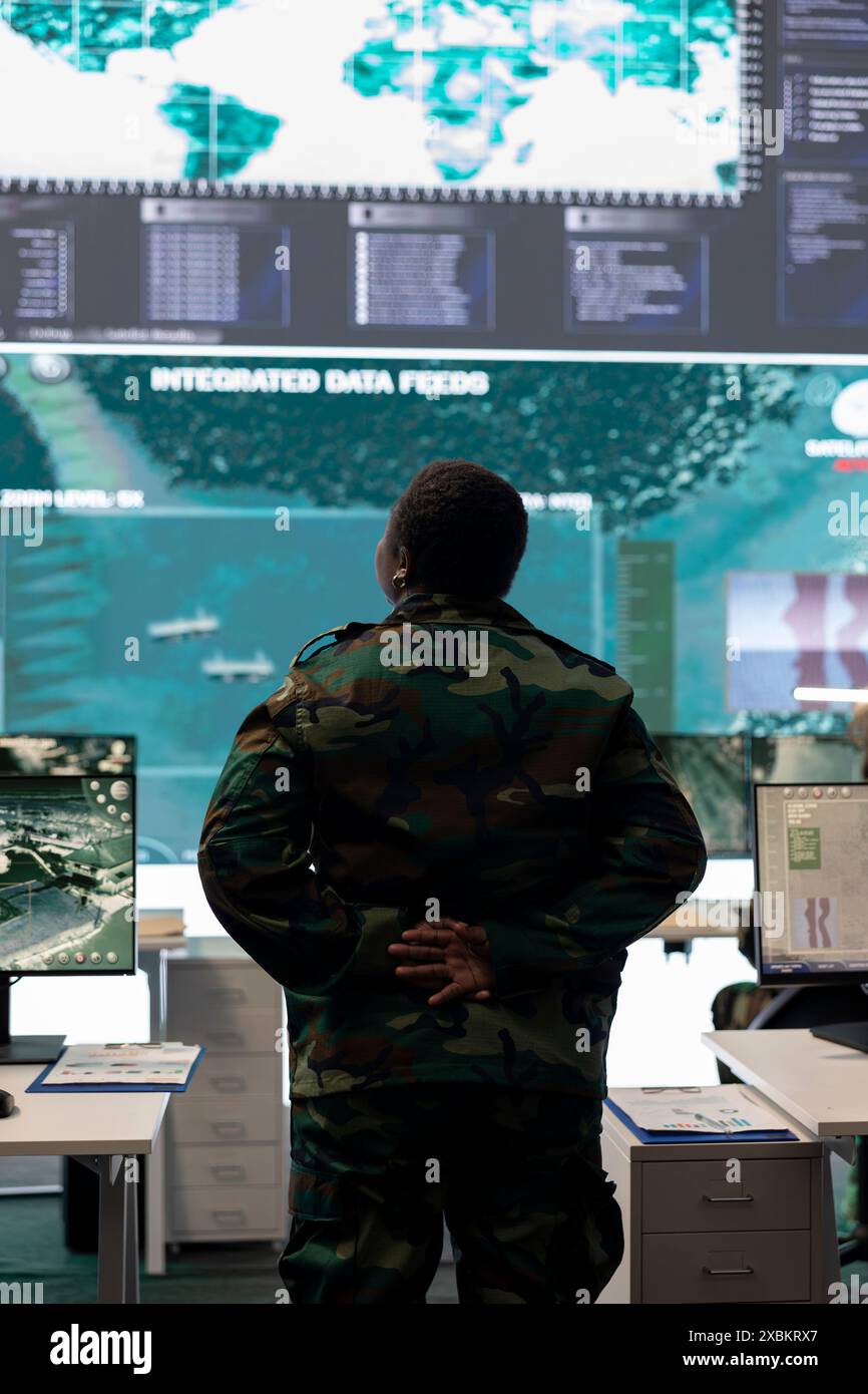 Woman army conscript examines big screen with surveillance imagery in ...