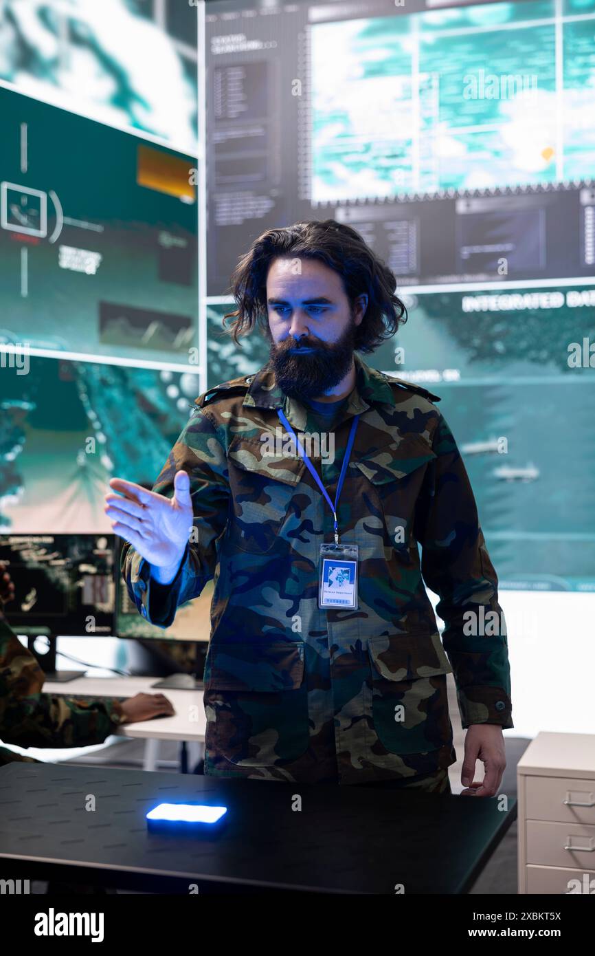 Army soldier examines real time data on a hologram 3d projection, reviewing defense operation ...