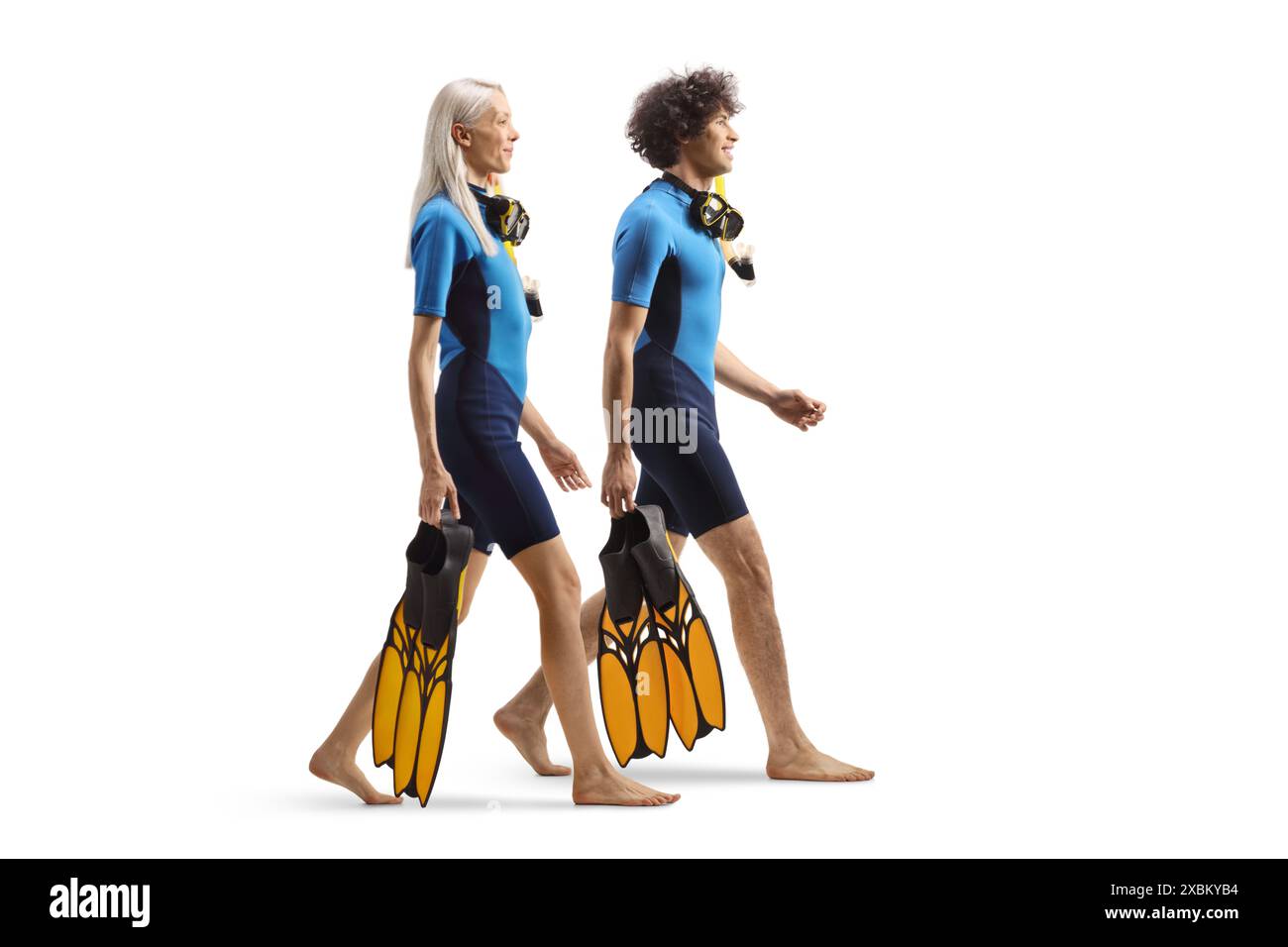 Full length profile shot of a man and woman in wetsuits carrying fins ...