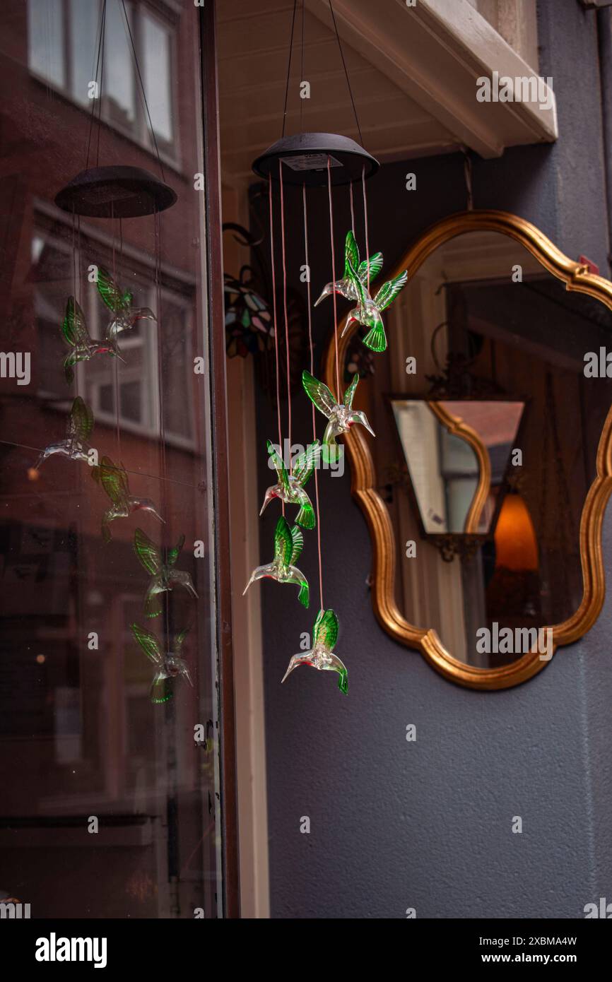 Glass birds in shades of green hang from a ceiling and are reflected in ...
