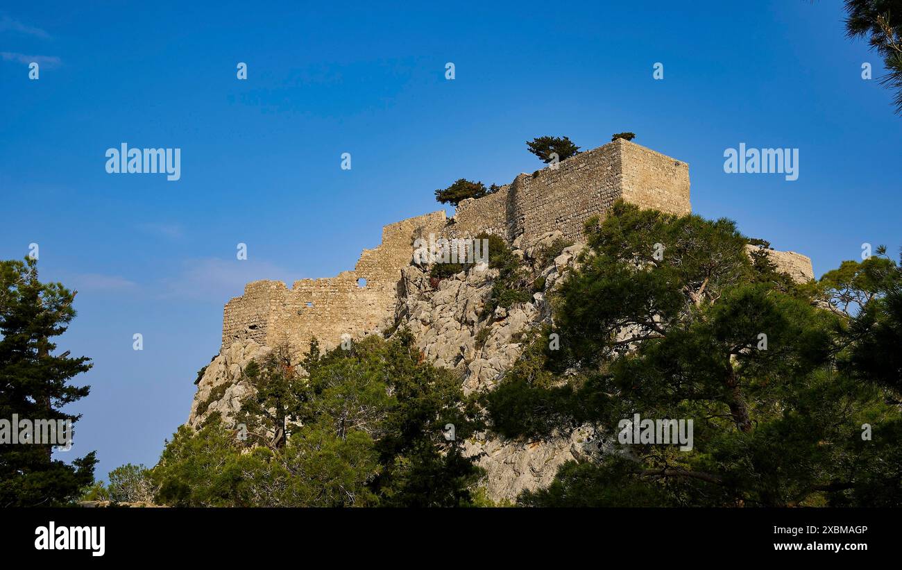 Medieval castle on a rocky hill surrounded by trees under a clear sky ...